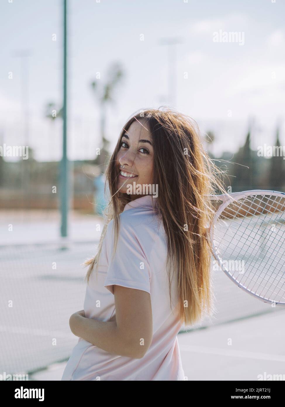 A vertical shot of a Hispanic female smiling and posing with a tennis ...