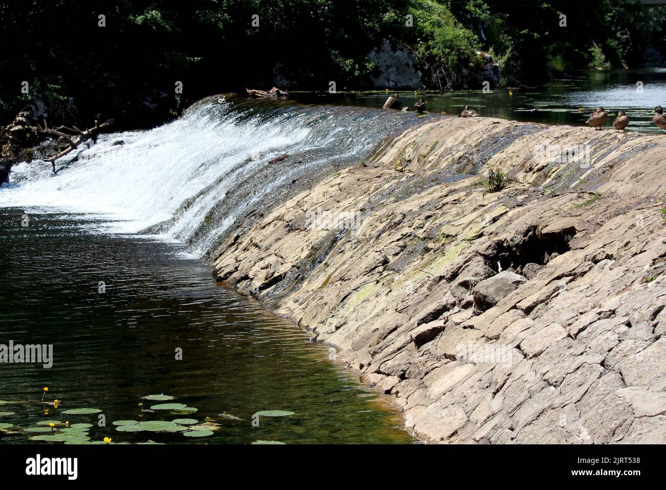 Stone and concrete old river dam with big hole in the middle of dry ...