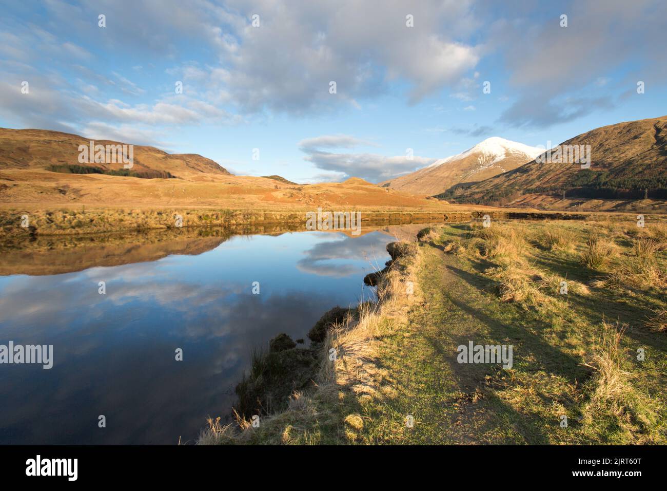 Area of Crianlarich, Scotland. Picturesque dusk view of the River Fillan with a snow capped Ben ...
