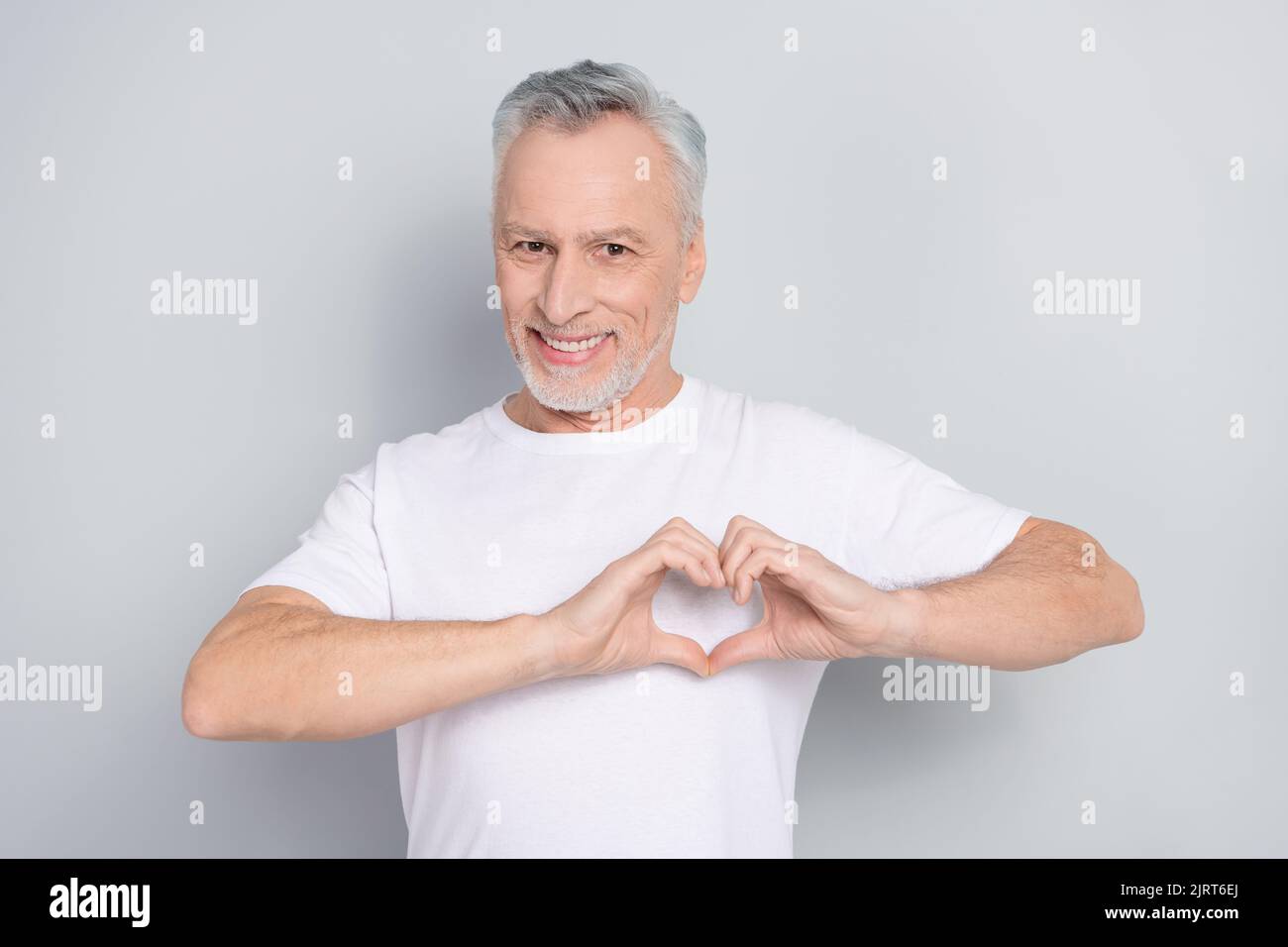 Photo of cute elder man show heart wear white t-shirt isolated on grey ...
