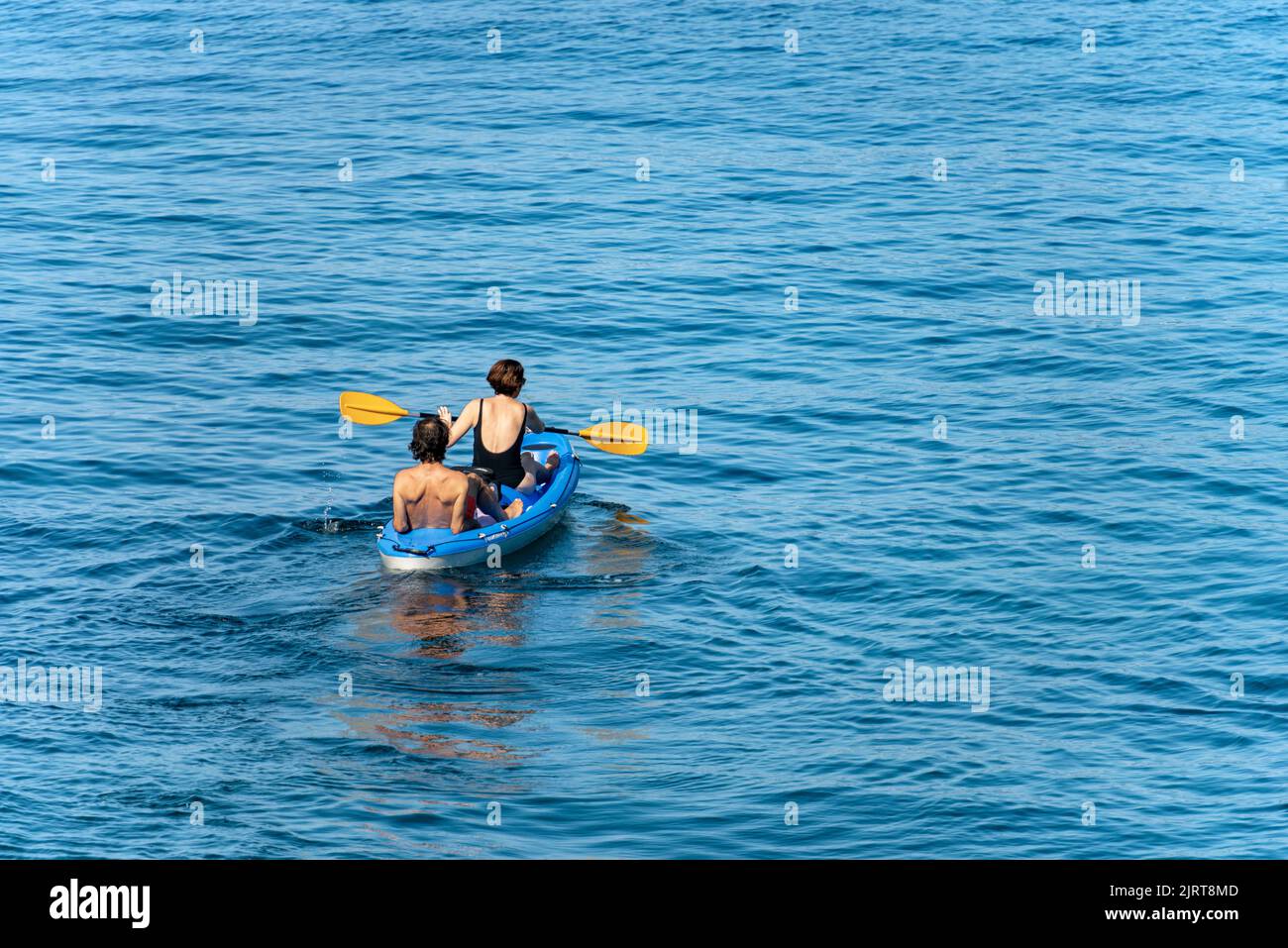 A mature couple aboard a blue kayak, paddling in the blue Mediterranean ...
