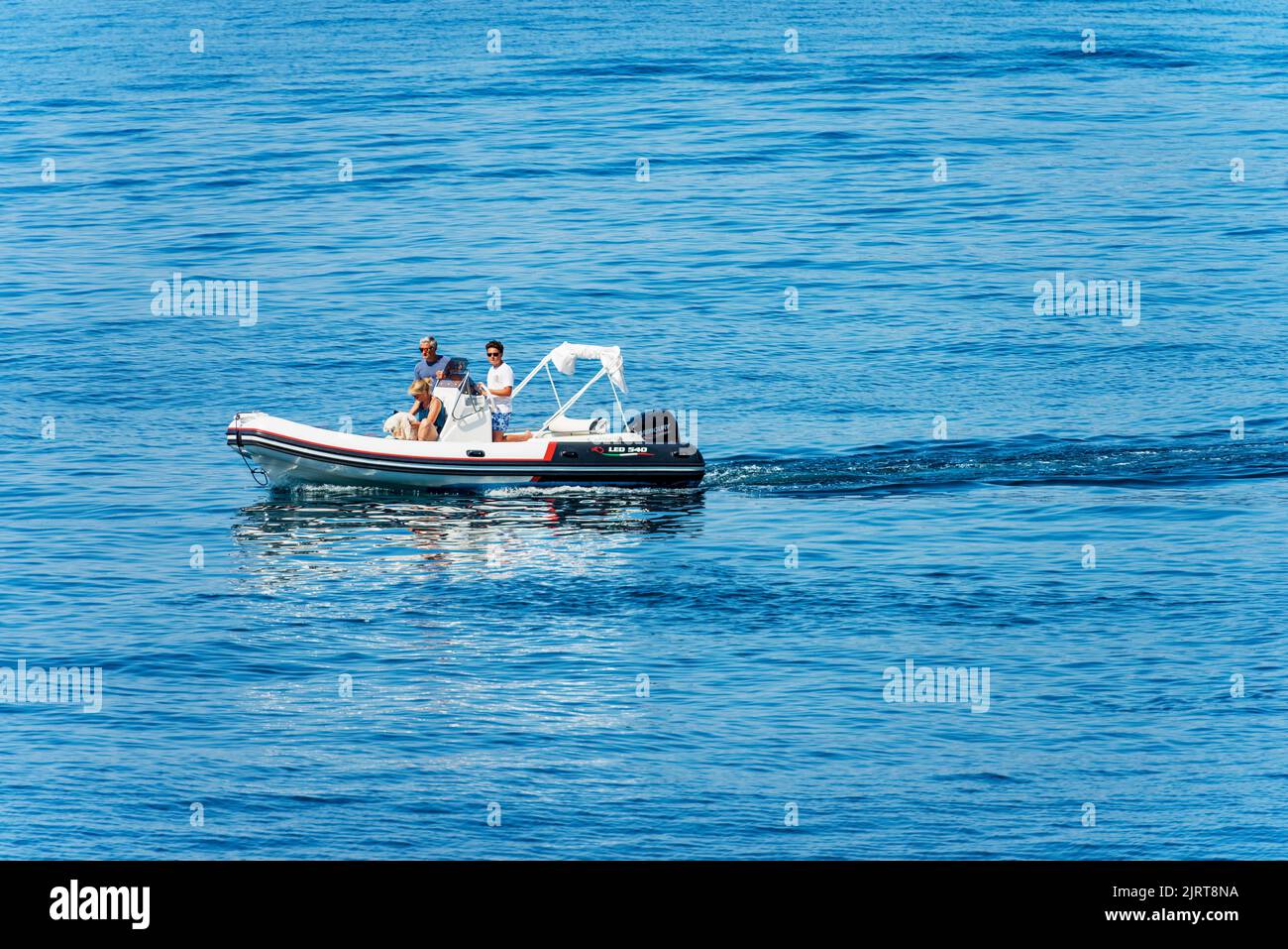 Small motorized dinghy with a family on board, on a sunny summer day in ...