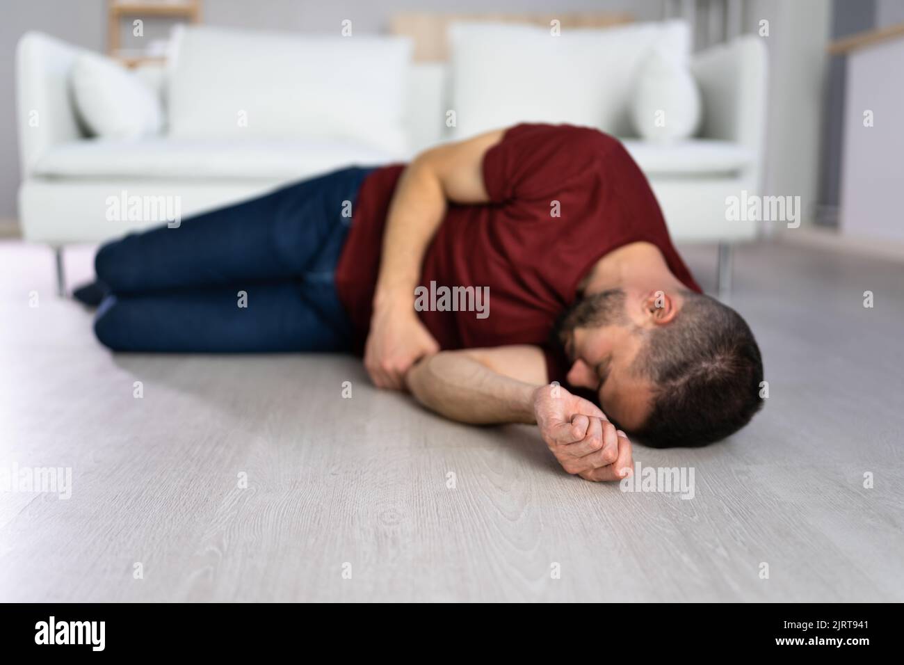 Unconscious Young Man Lying On Floor In Living Room Stock Photo - Alamy