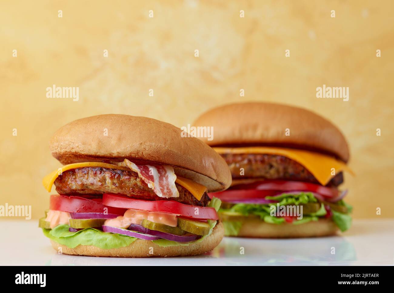 two fresh burgers on yellow background, selective focus Stock Photo - Alamy