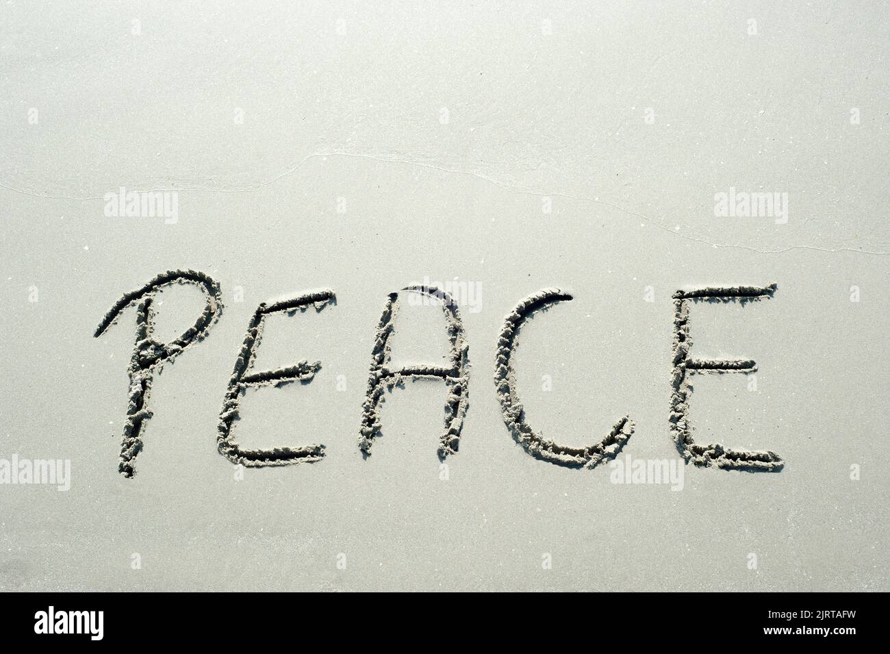 Concept or conceptual Peace text handwritten in sand on a beach in an ...