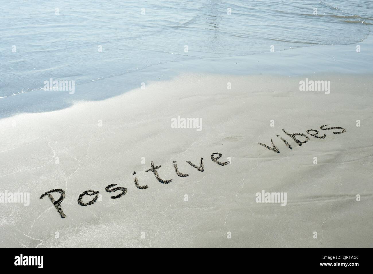 Concept or conceptual Positive vibes text handwritten in sand on a ...