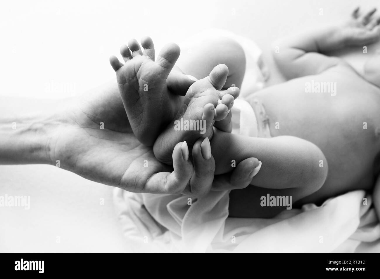 Hands of parents. The legs, feet of the newborn in the hands of mom and ...