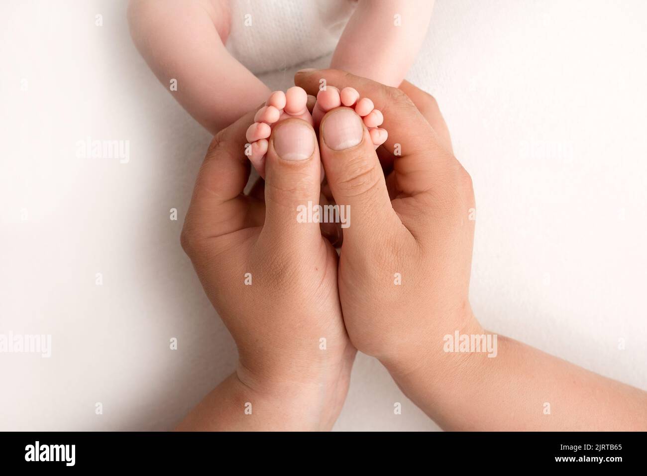 Hands of parents. The legs, feet of the newborn in the hands of mom and ...