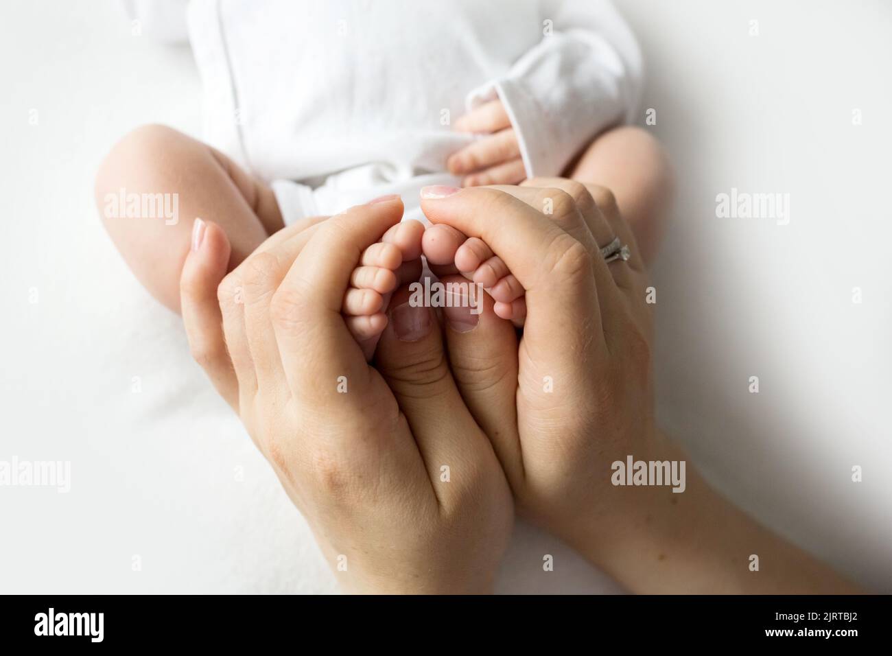Hands of parents. The legs, feet of the newborn in the hands of mom and ...