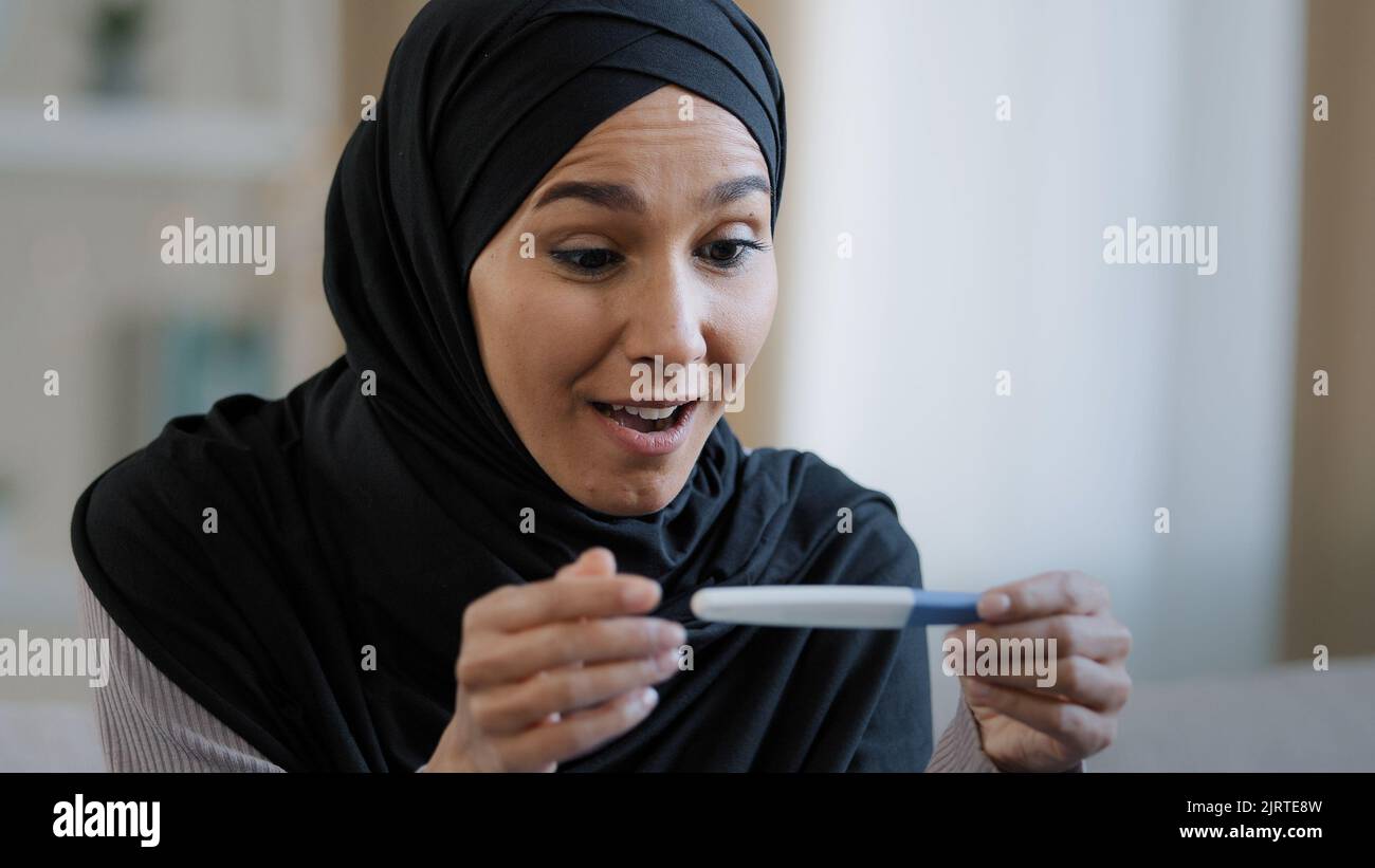 Joyful islamic young woman in hijab smiling happily holding pregnancy ...