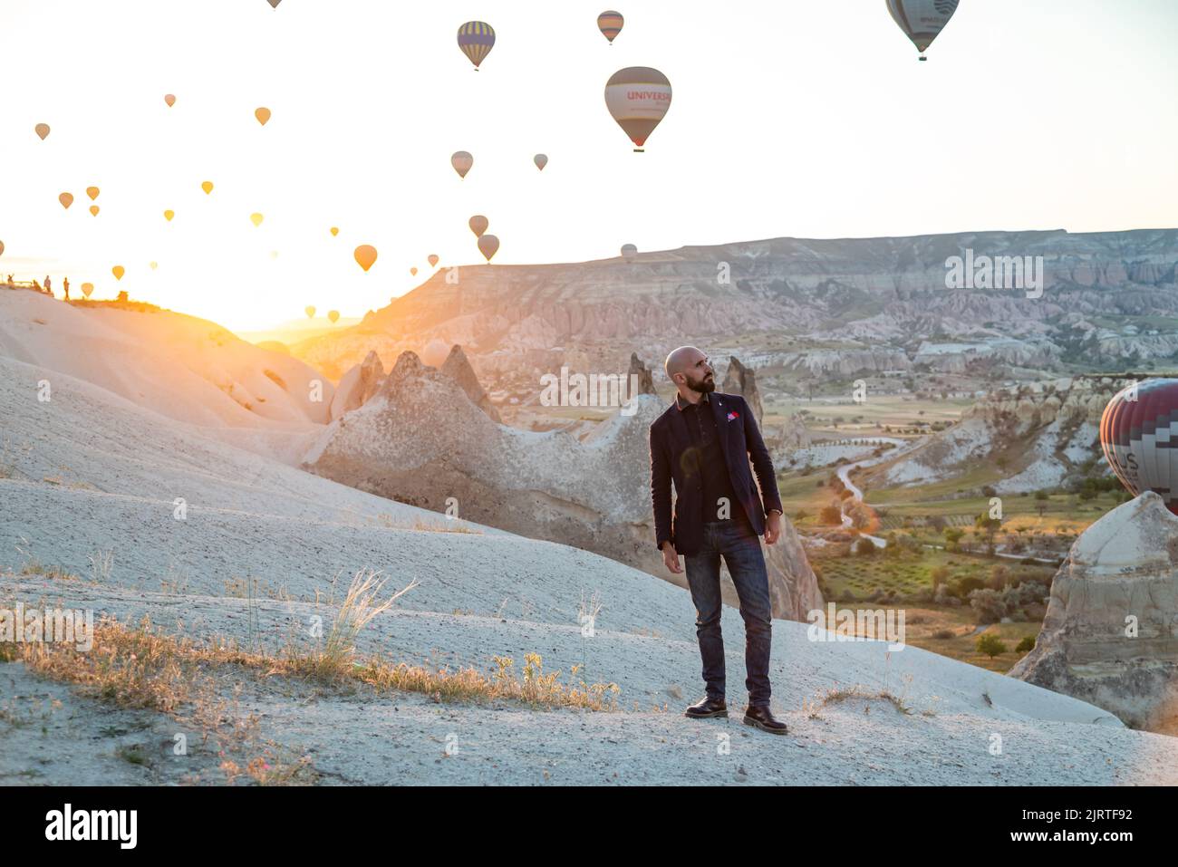 A handsome bald man with beard in the suit posing in the Chimney valley ...
