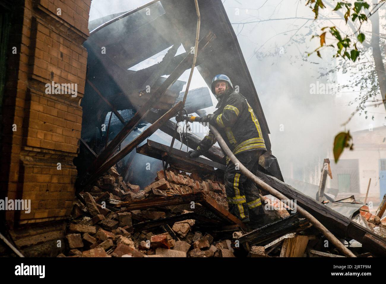 A firefighter climbs over rubble to extinguish a fire caused from ...