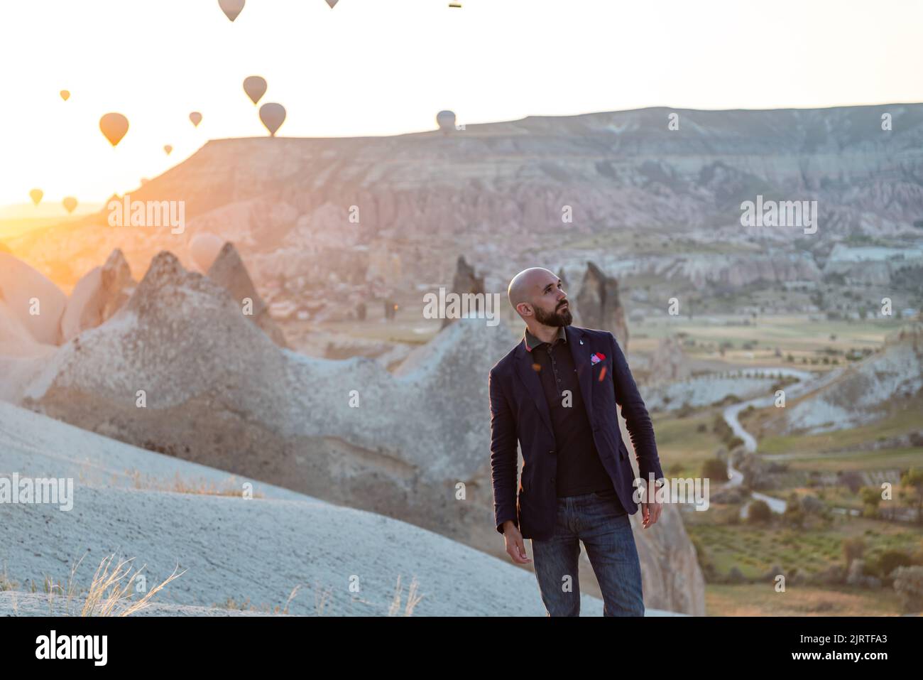 A handsome bald man with beard in the suit posing in the Chimney valley ...