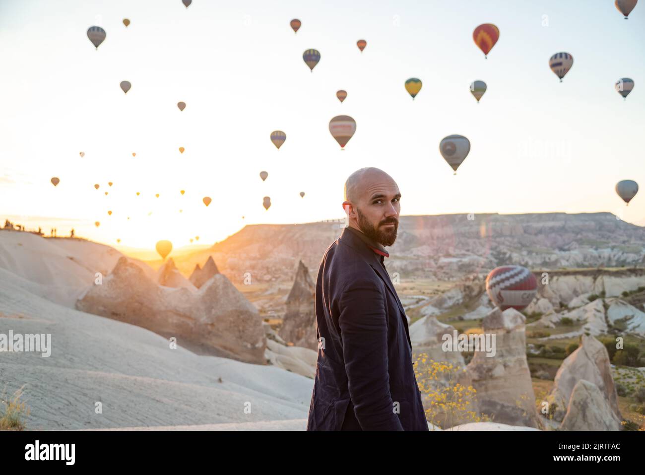 A handsome bald man with beard in the suit posing in the Chimney valley ...