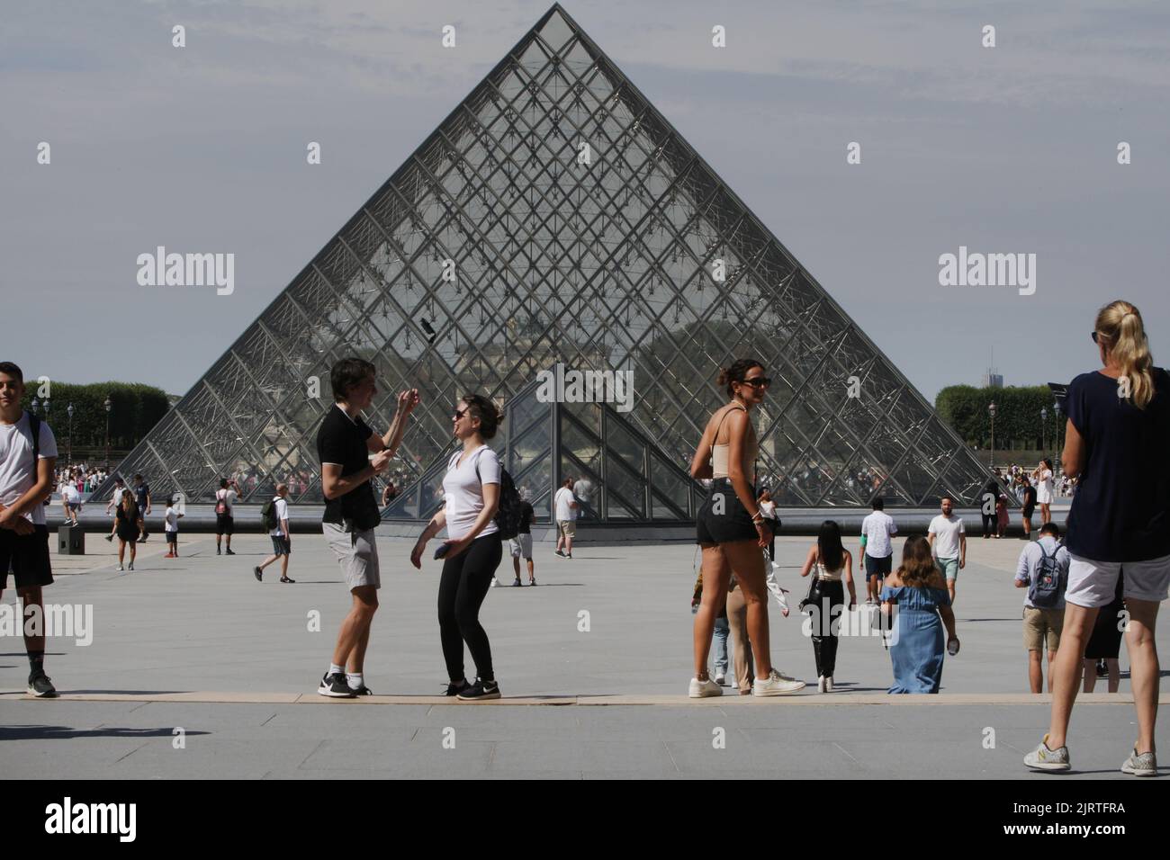 Tourists enjoys near Pyramid at the Louvre Museum during a hot summer ...