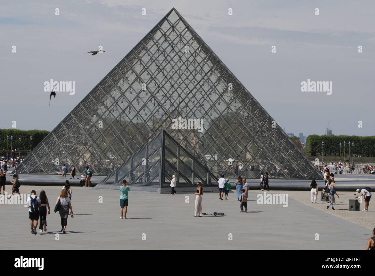 Tourists enjoys near Pyramid at the Louvre Museum during a hot summer ...