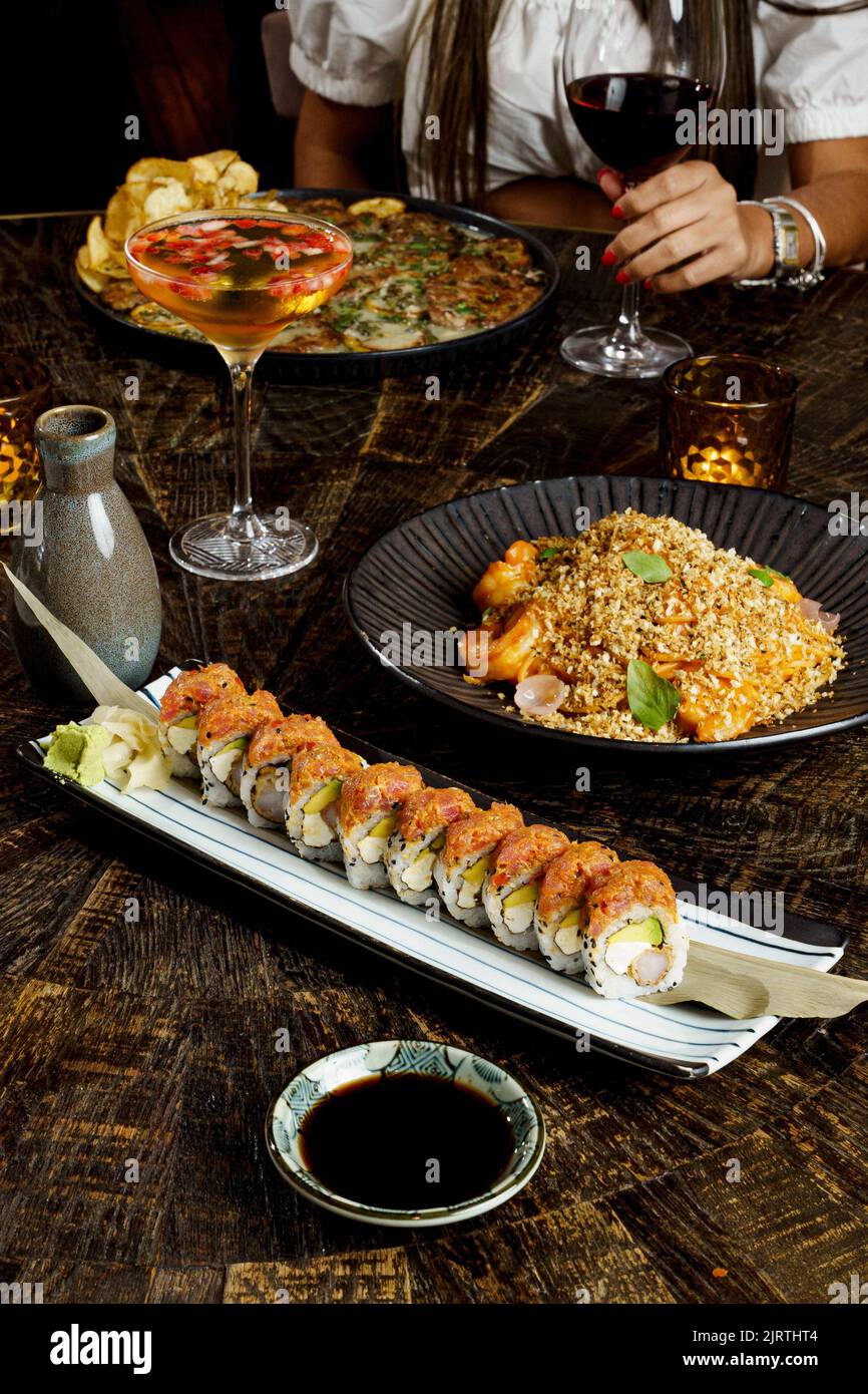 Restaurant sushi rolls on a full table with food Stock Photo - Alamy