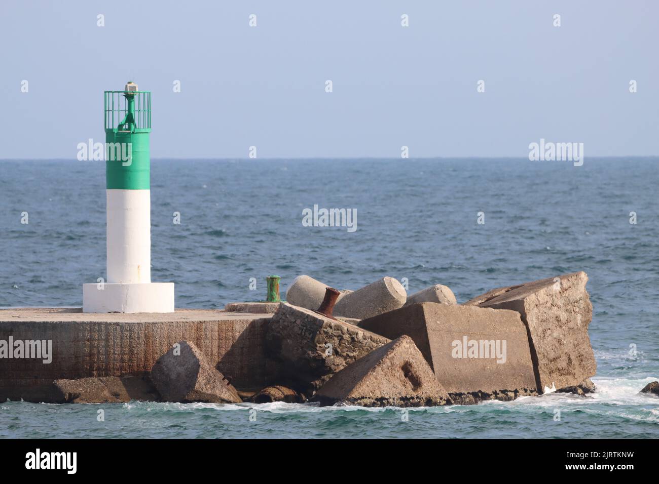 A breakwater of large concrete blocks in the sea with a small white and ...