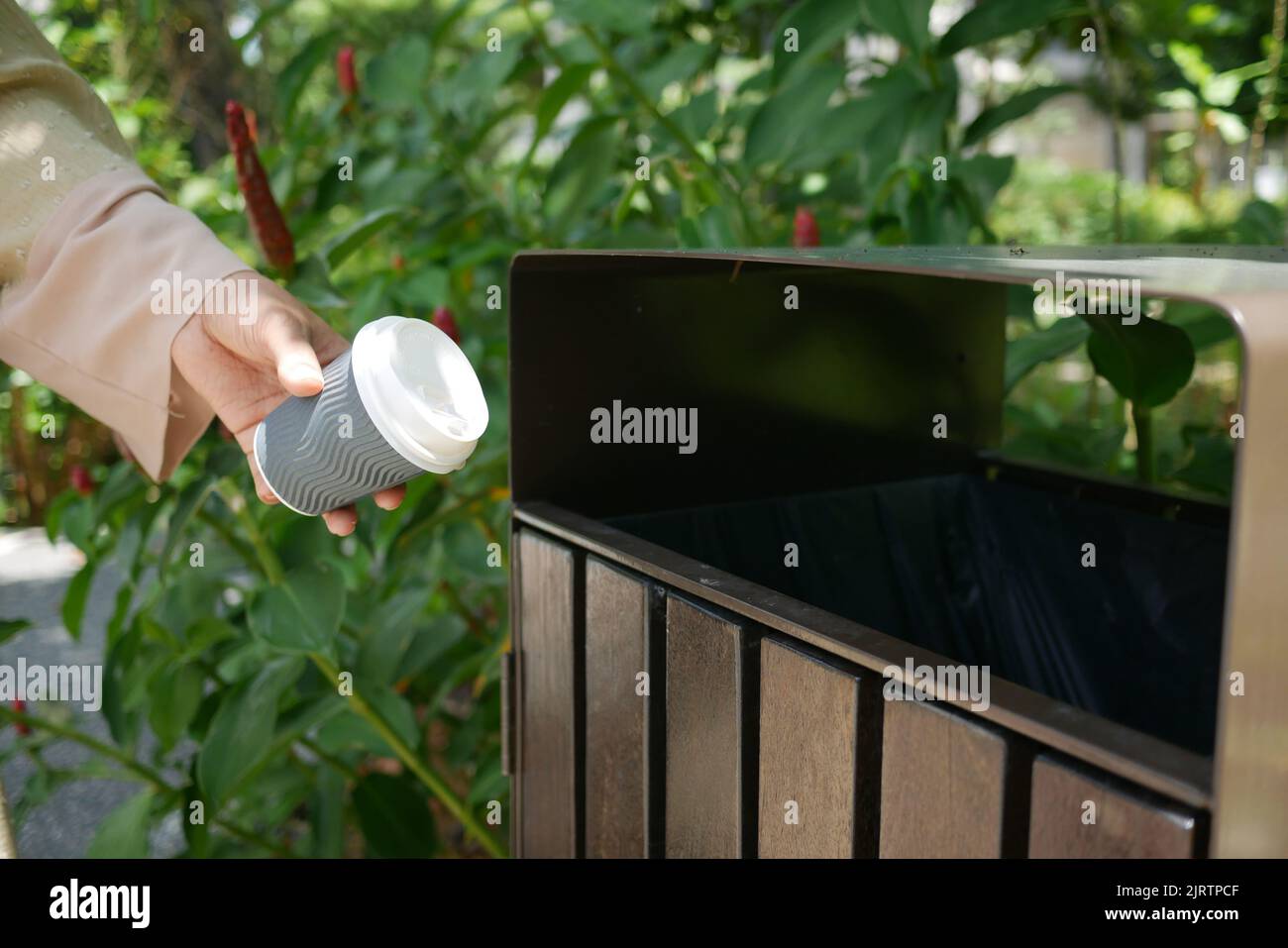 women hand throwing an empty coffee paper cup in the garbage trash or ...