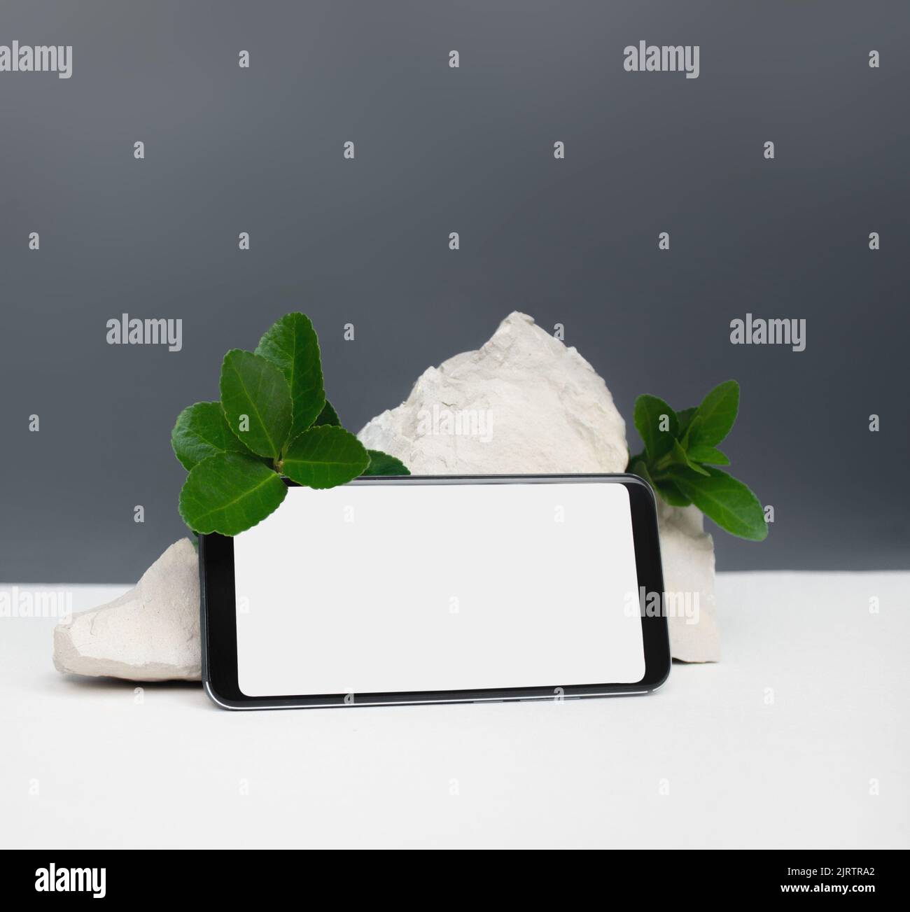 Mobile phone with white screen and stone on a white-gray background ...