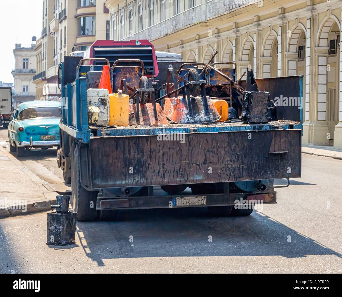 A maintenance truck with old wheelbarrows in the back is parked in the ...