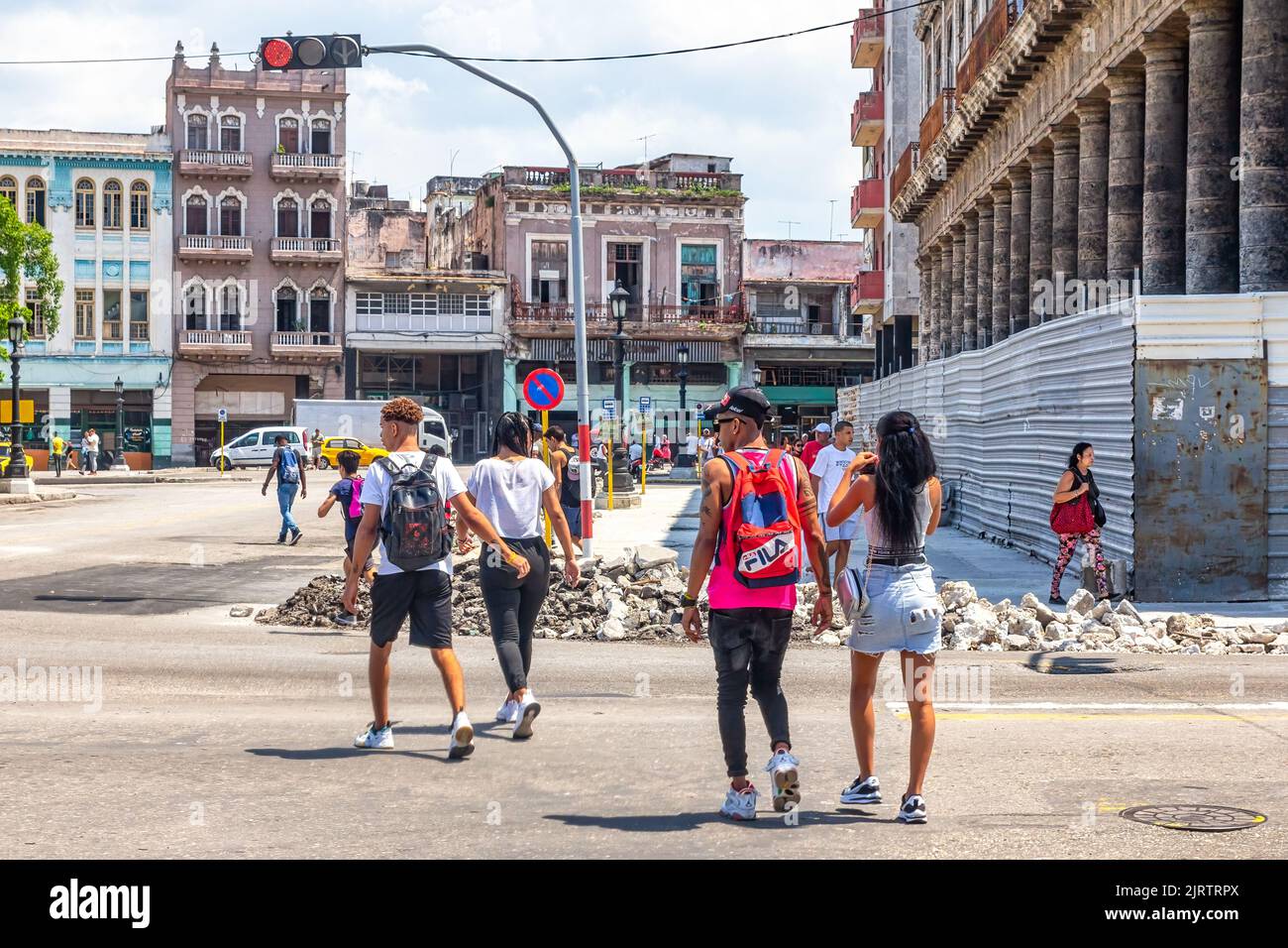 A group of young Cuban people cross the street towards a pile of rubble ...