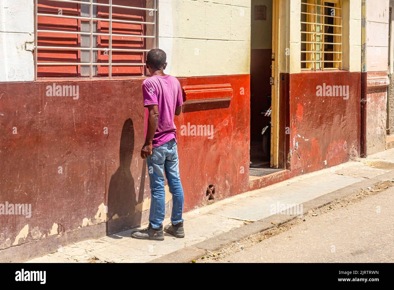 A Cuban afro-caribbean man speaks through a window with people on the ...