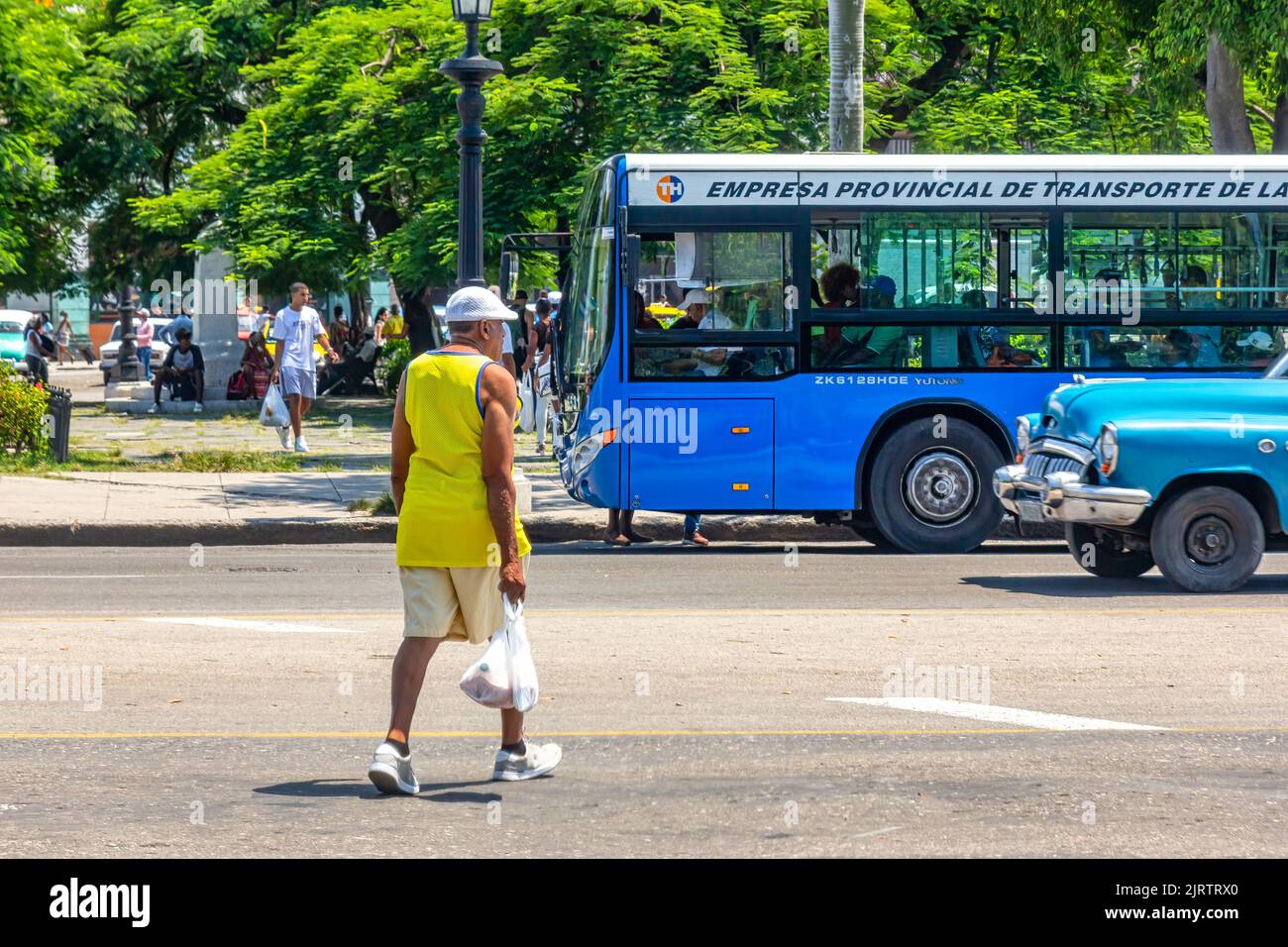 A Cuban man in yellow clothes crosses a city street where a public ...