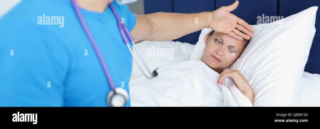 Doctor keeps hand on forehead of sick woman on bed Stock Photo - Alamy