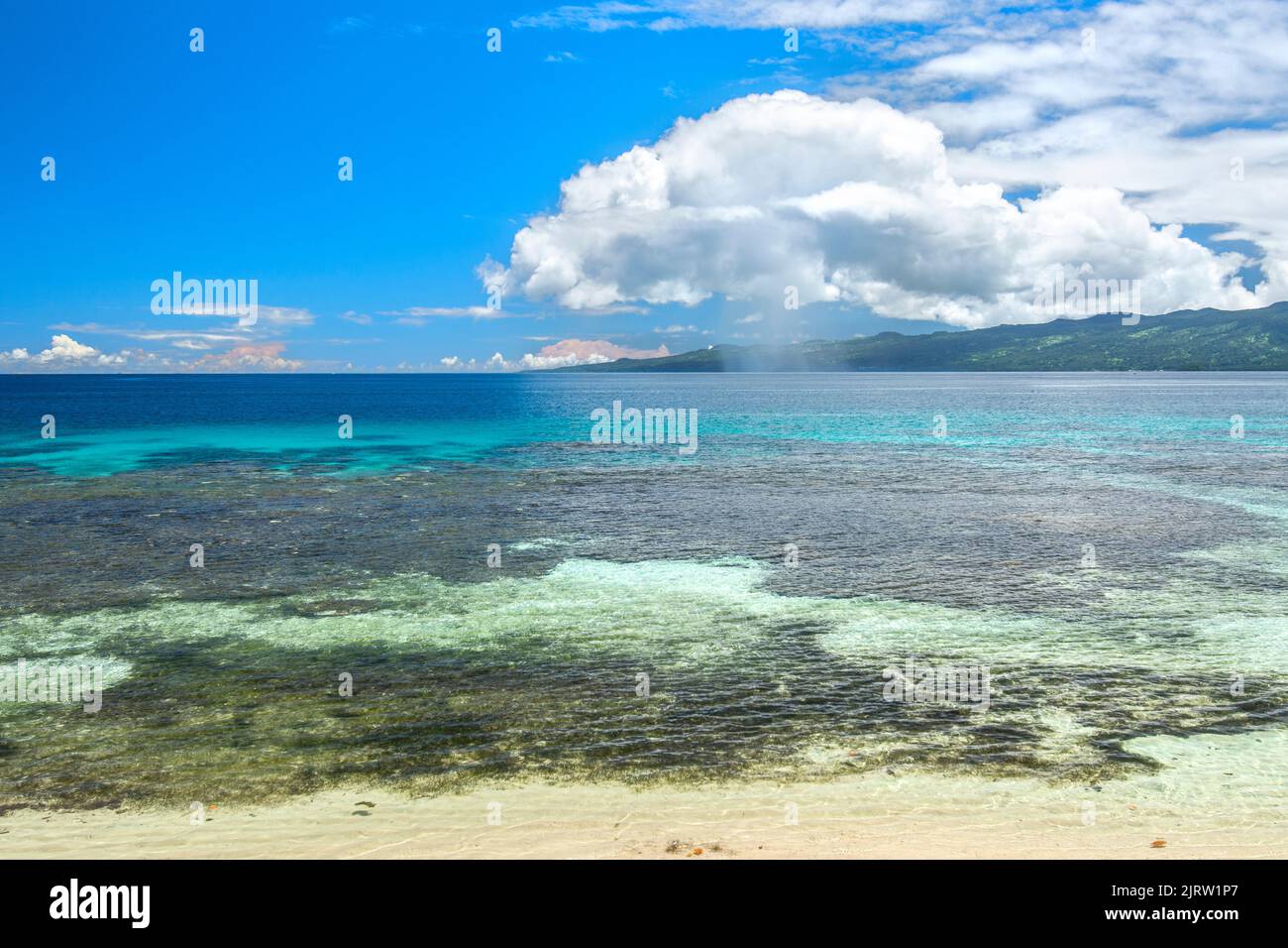 A beautiful tropical beach shows the clear water and vibrant sky of ...