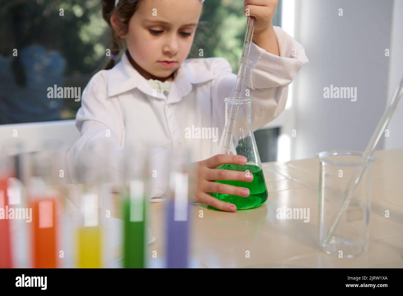 Focus on flat-bottomed flask with solution and little girl's hand using ...