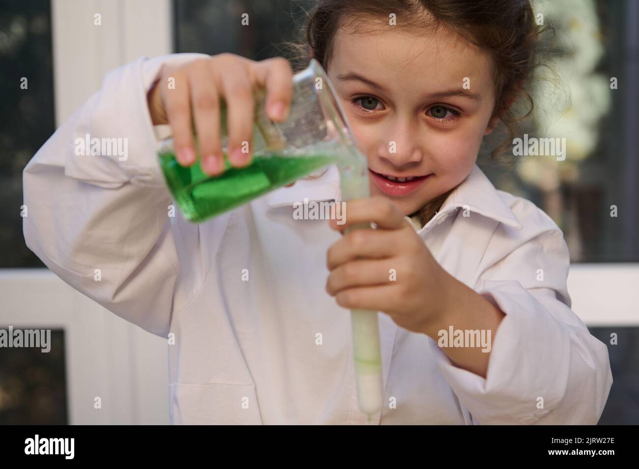 Homeschooling little girl learning about science, pouring reagent or ...