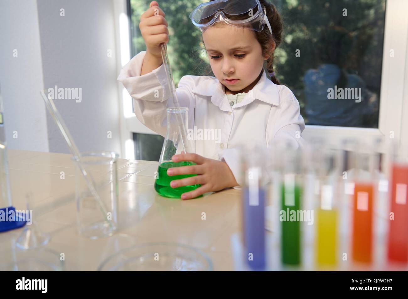Little European girl making scientific experiments, inspired by ...