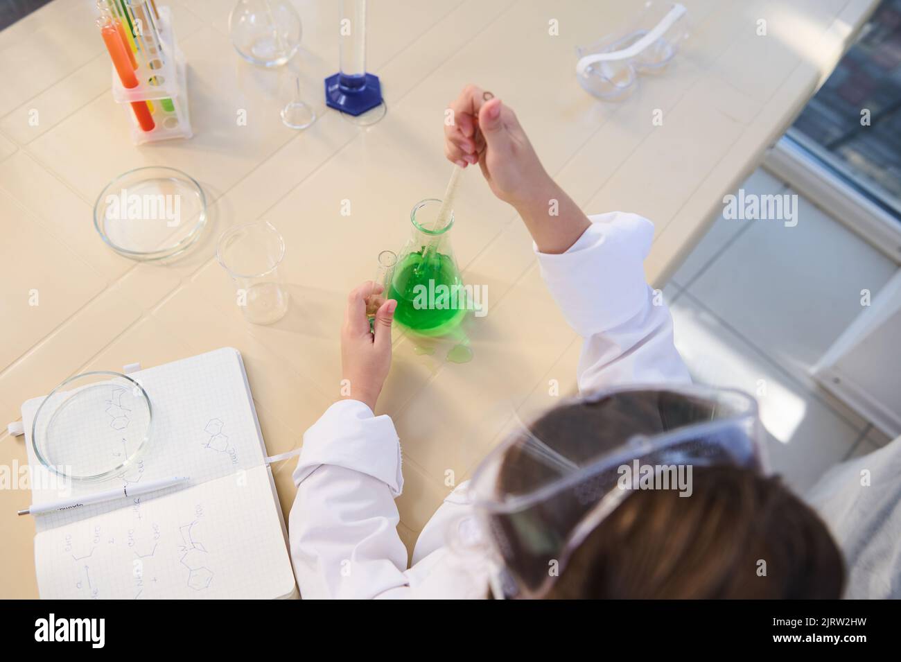 Top view schoolchild using a test tube, dripping few drops of a ...