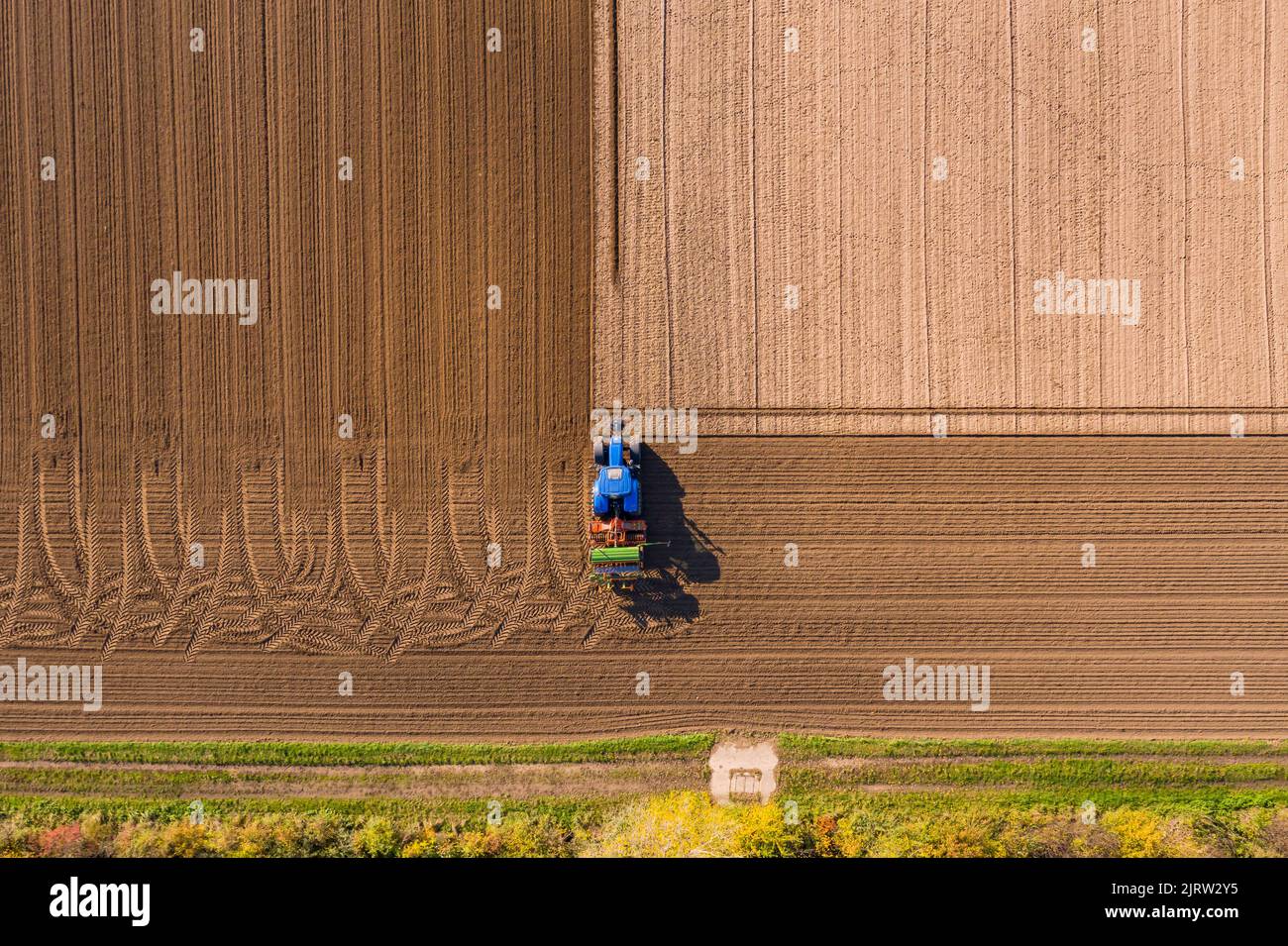 Aerial view with tire tracks of a distinctive blue tractor plowing a ...