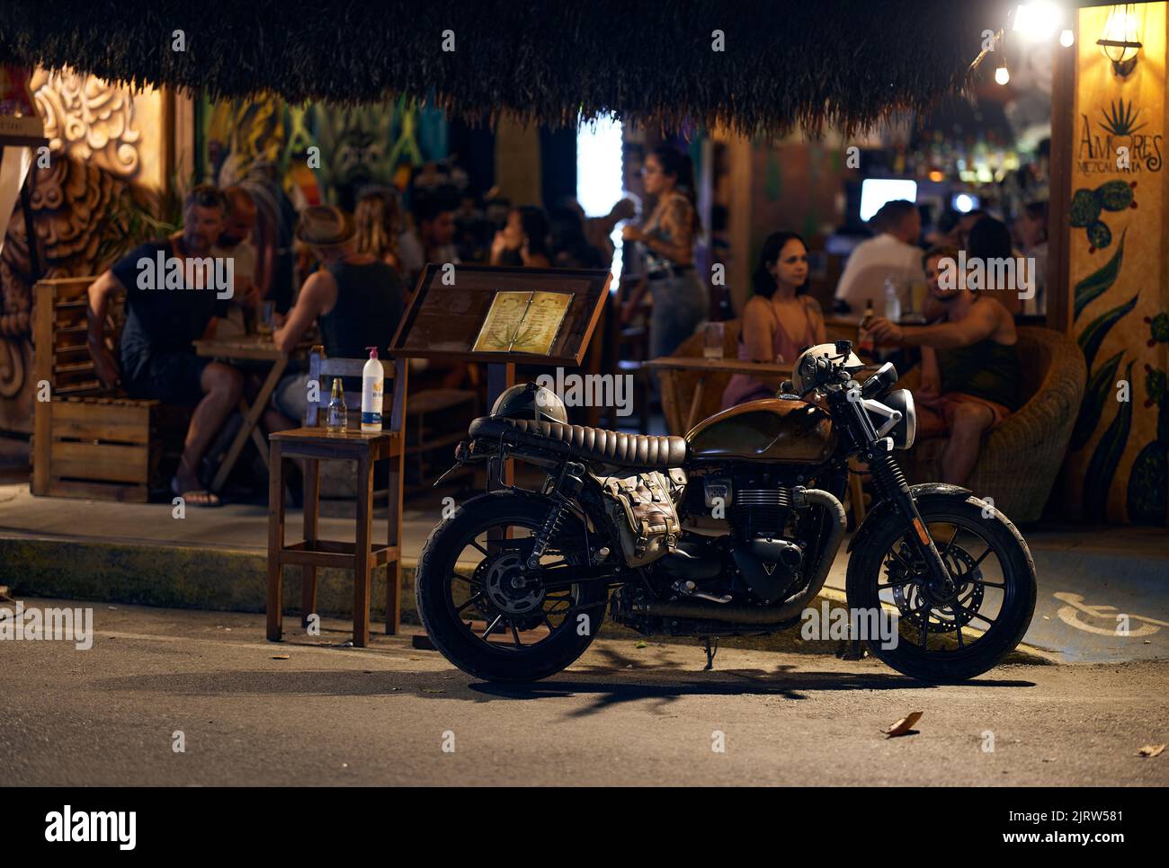 A motorcycle parked in front of a crowded bar during nighttime Stock ...