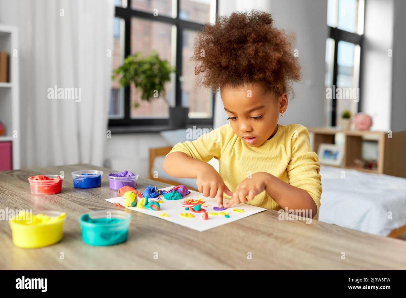 little girl with modeling clay playing at home Stock Photo - Alamy
