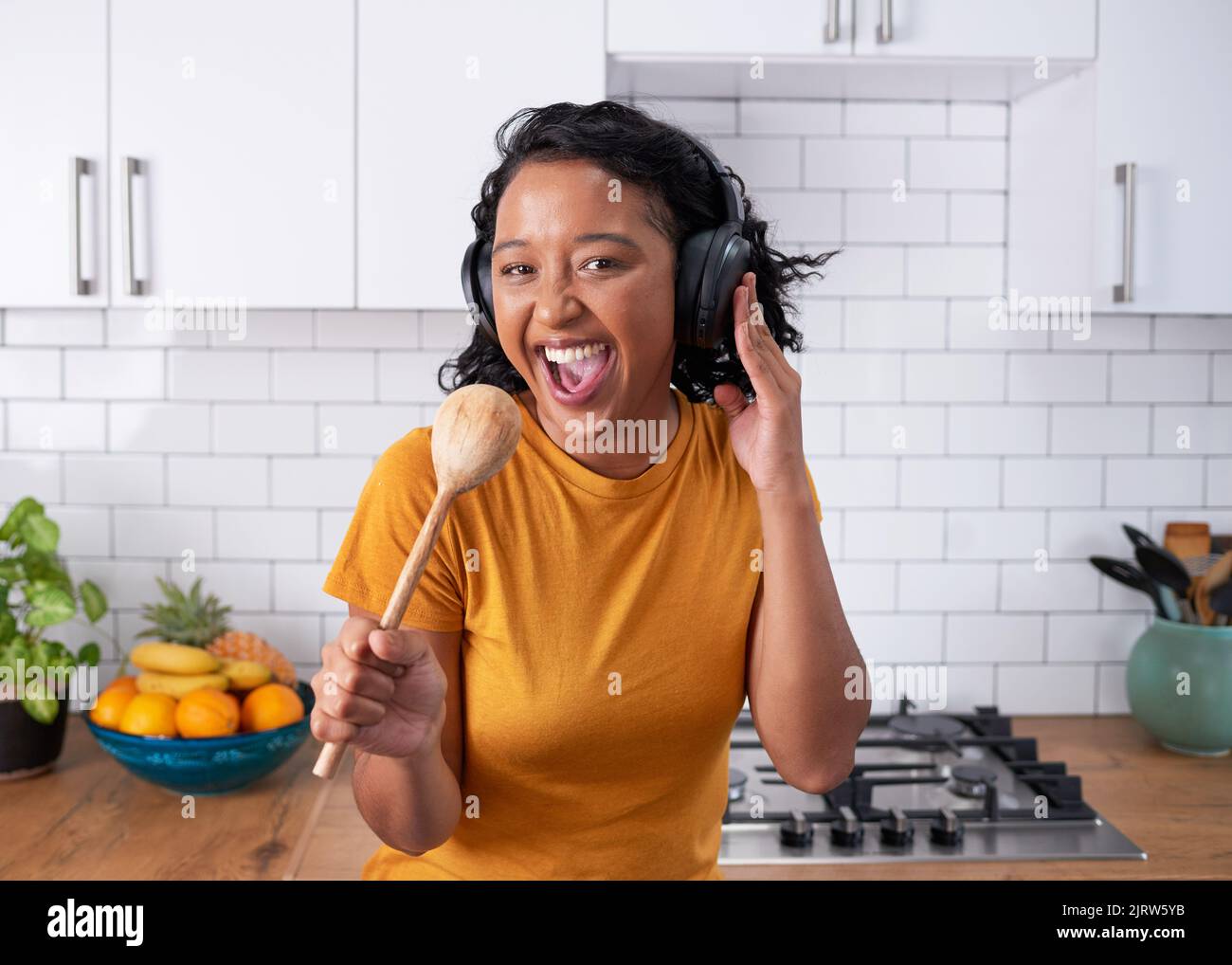 A young funky woman sings with wooden spoon in a modern kitchen Stock ...