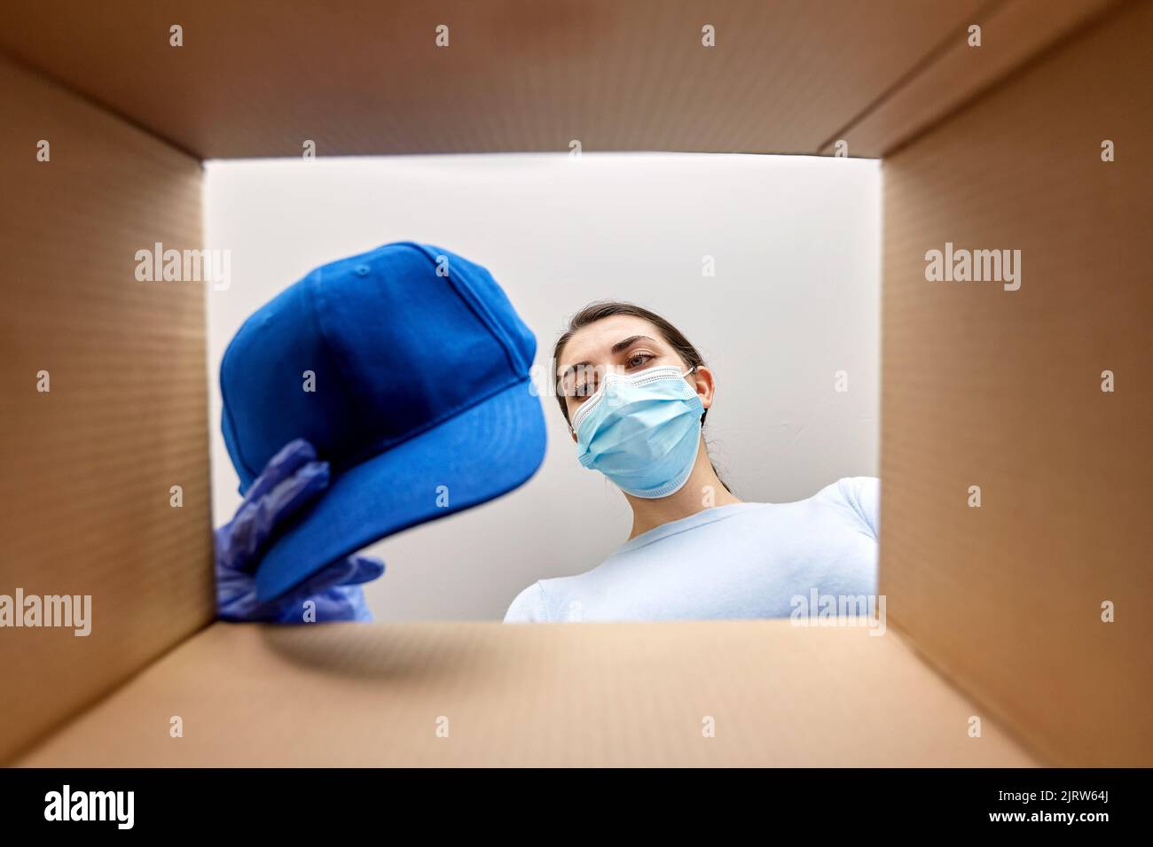 woman in mask opening parcel box with clothes Stock Photo - Alamy