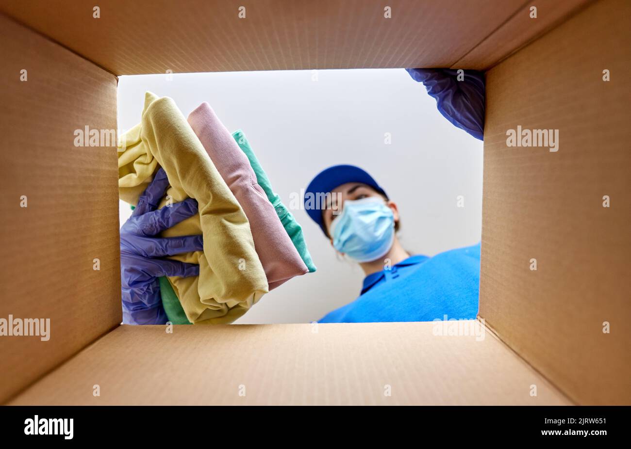 woman in mask packing clothes to parcel box Stock Photo - Alamy