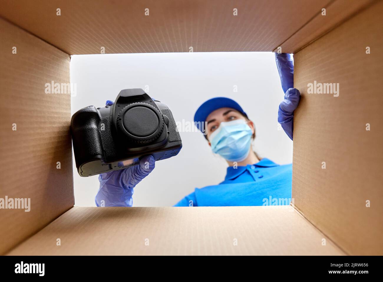 woman in mask packing camera into parcel box Stock Photo - Alamy