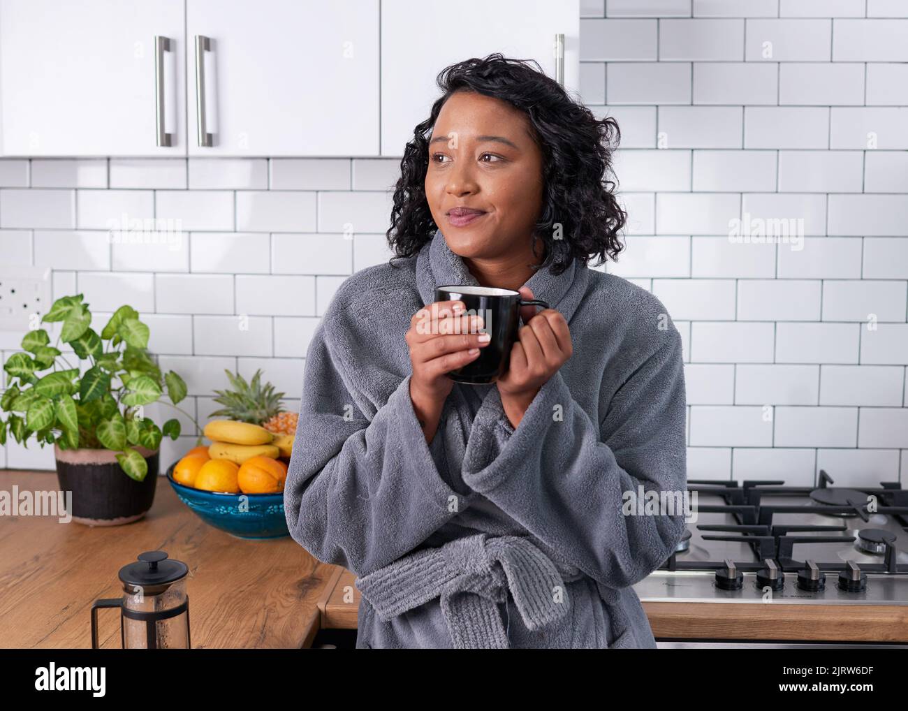 A young woman enjoys a moment waking up while she drinks coffee in the ...