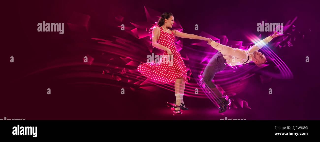 Excited man and woman, professional dancers dancing lindy hop over dark ...