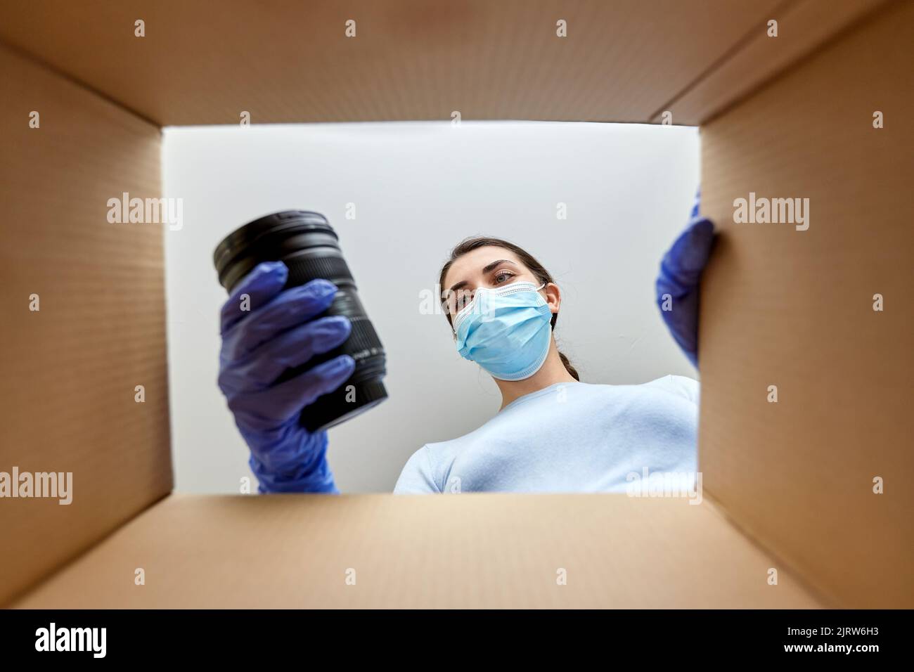 woman in mask packing camera into parcel box Stock Photo - Alamy