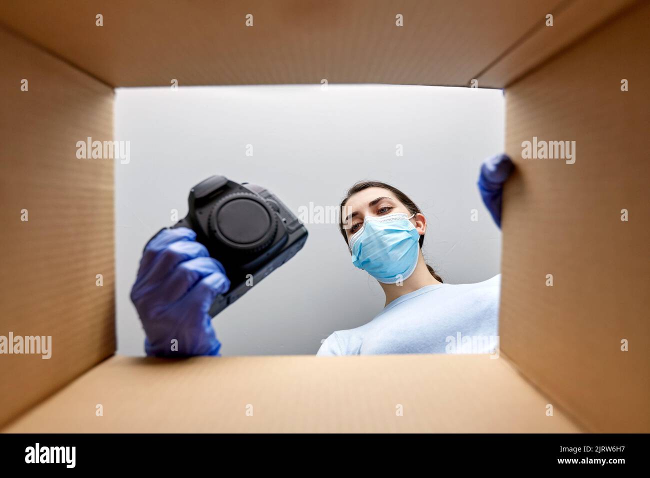 woman in mask packing camera into parcel box Stock Photo - Alamy