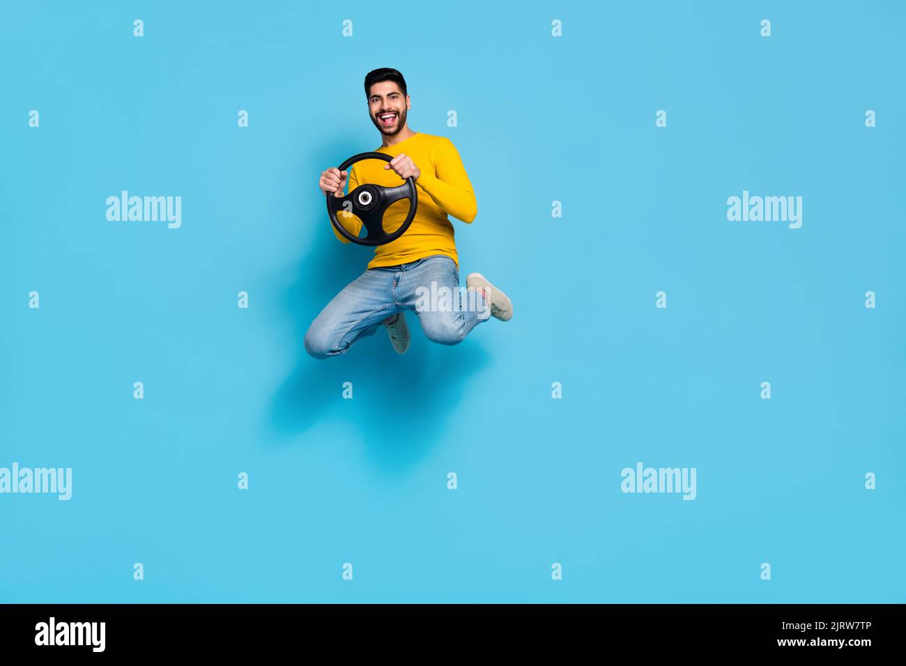 Full size portrait of overjoyed handsome person arms hold wheel jump ...
