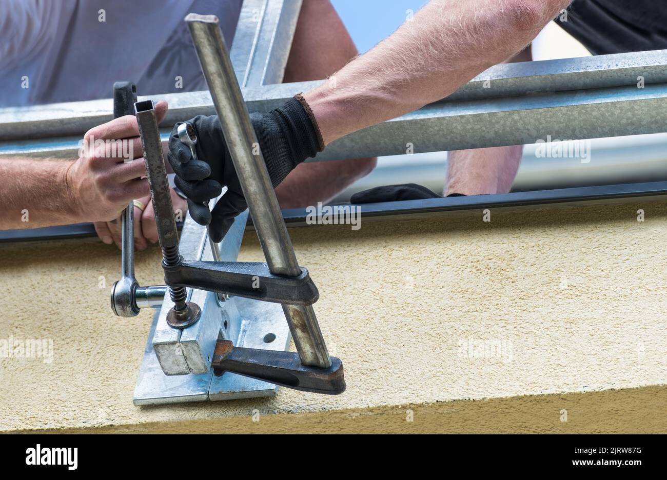 Construction workmans at assembling steel guard rail to building wall ...