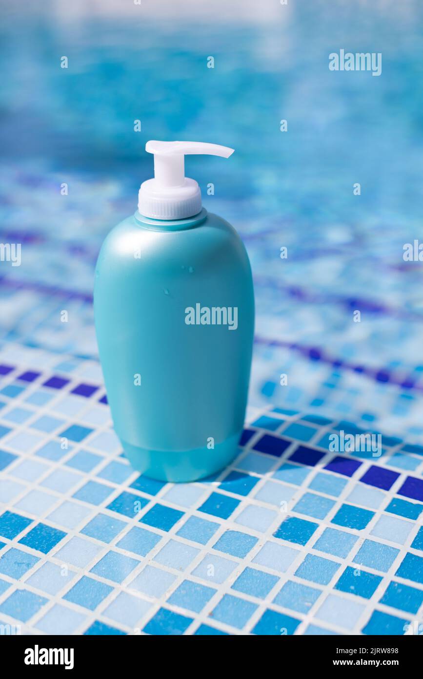 Sunscreen bottle is on steps in blue water of swimming pool Stock Photo ...