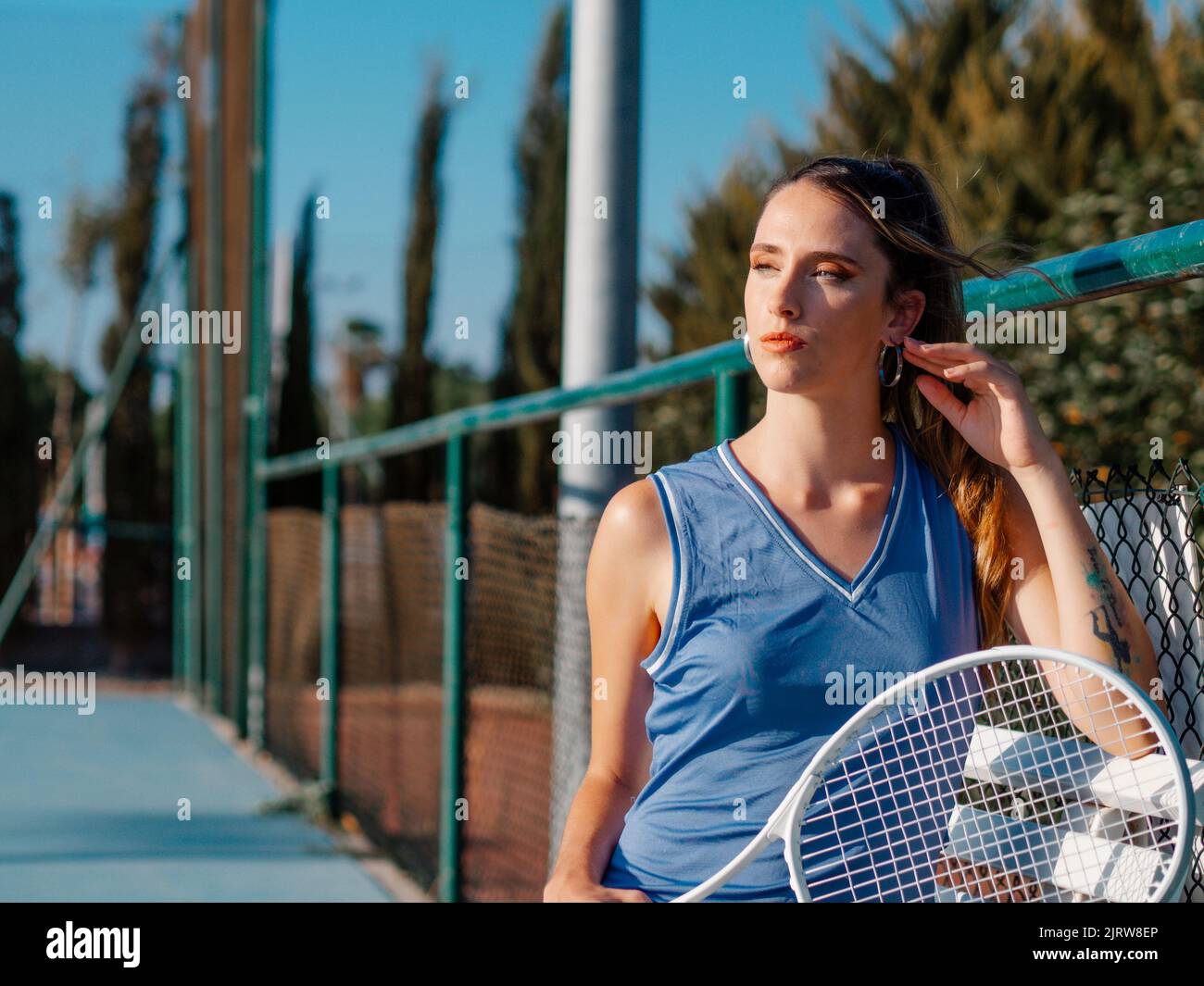 A caucasian female tennis player sitting on a bench in a court with a ...