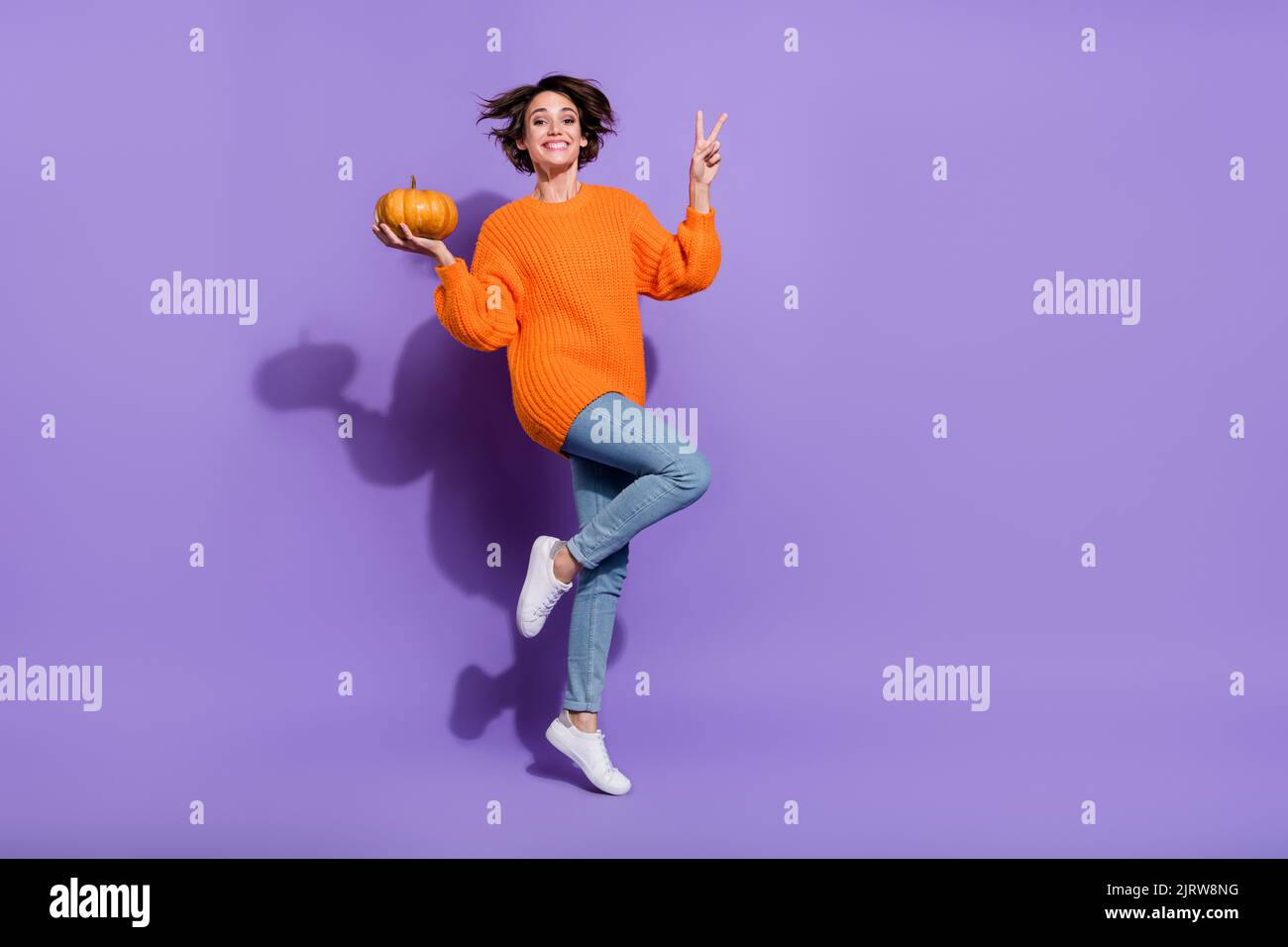 Full length body size view of lovely cheery girl jumping with pumpkin ...